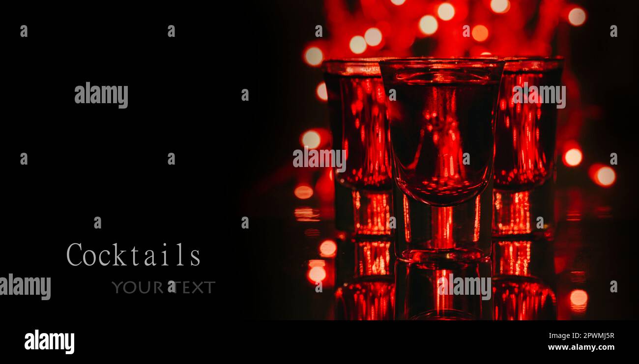 Red alcohol cocktails in shot glasses over red bokeh light and black ...
