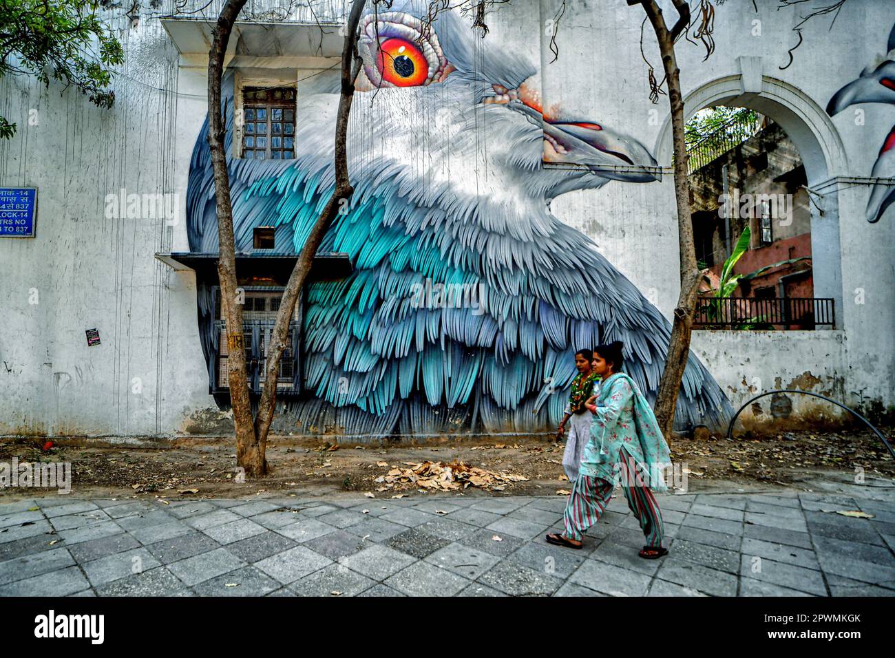 Delhi, India. 21st Apr, 2023. Women walk past a mural in the open air ...