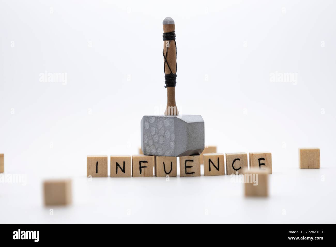 The hammer is standing on the wooden cubes with the word INFLUENCE ...