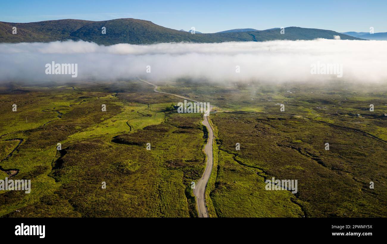 Aerial view of a road running through a deserted valley with low cloud ...