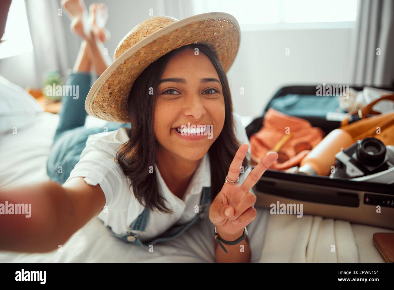 Portrait, travel and selfie by woman on bed with luggage, smile and ...