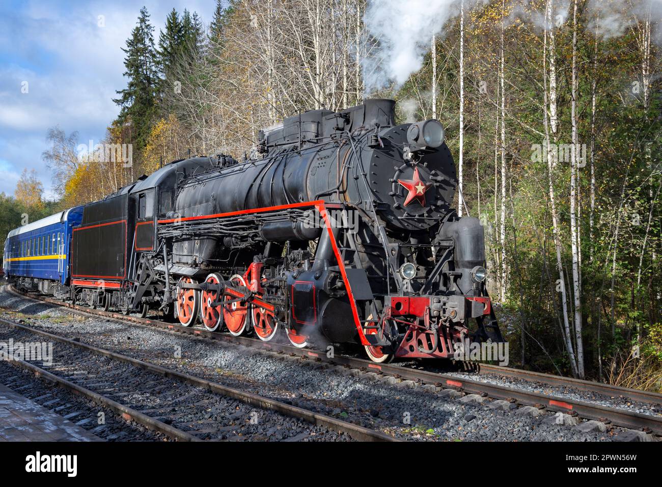 A steam locomotive with a retro train on a forest stretch. Russia Stock ...