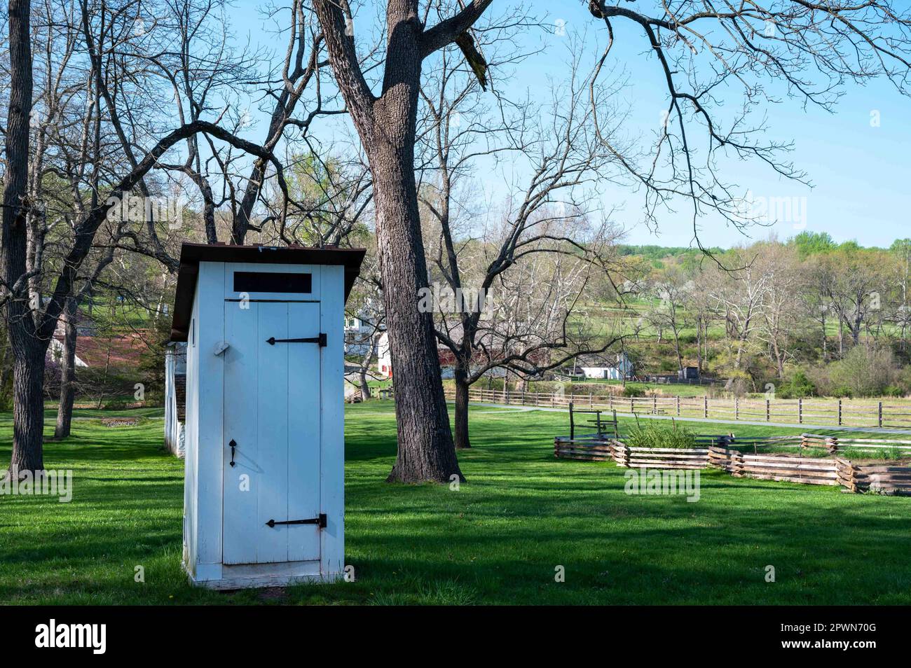 White colonial Pennsylvania outhouse in grass with village background Stock Photo - Alamy