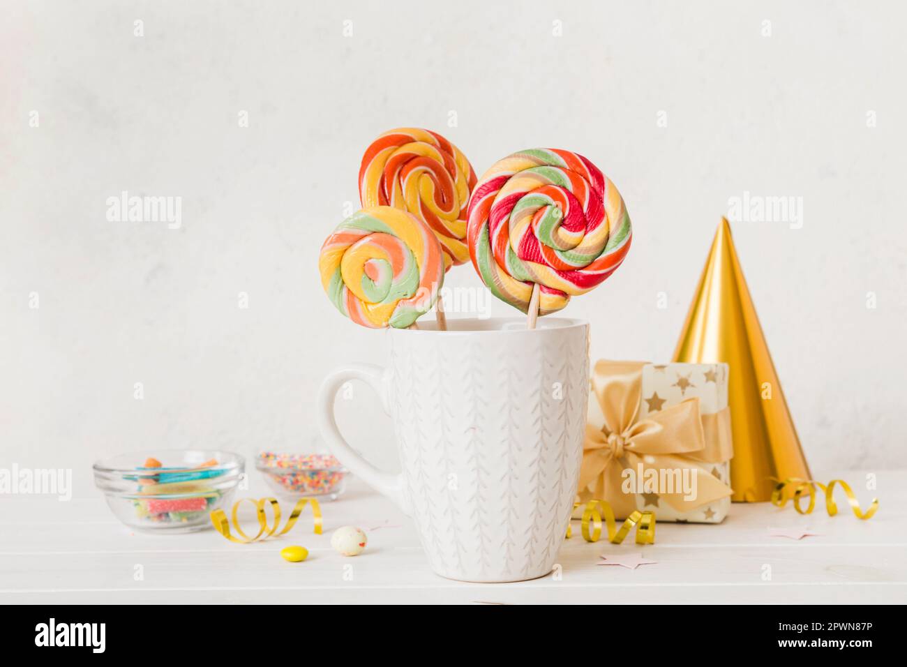 Colorful candies in cup on table on light background background. Large ...