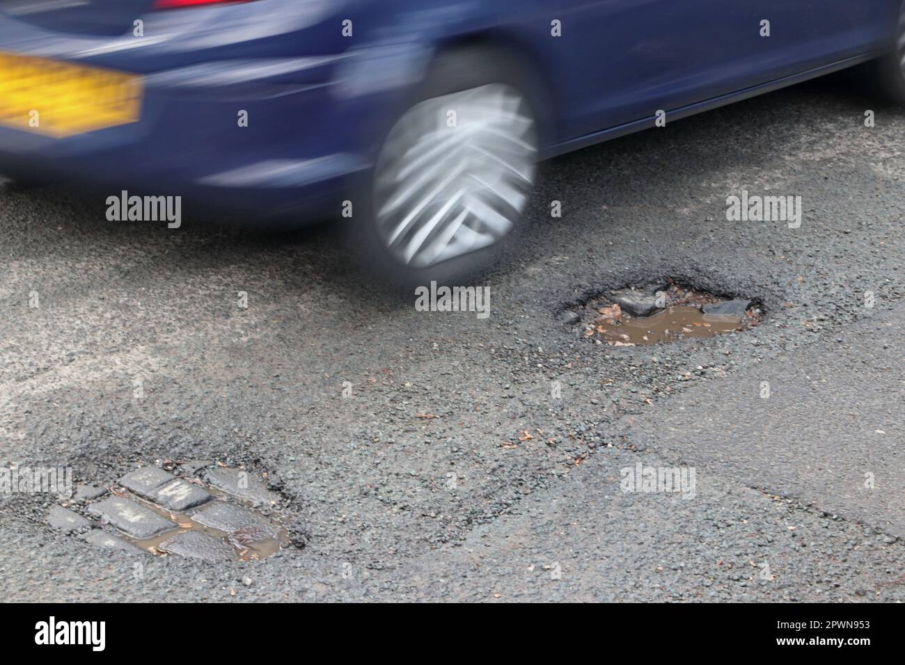 Car passing potholes in road surface Stock Photo - Alamy