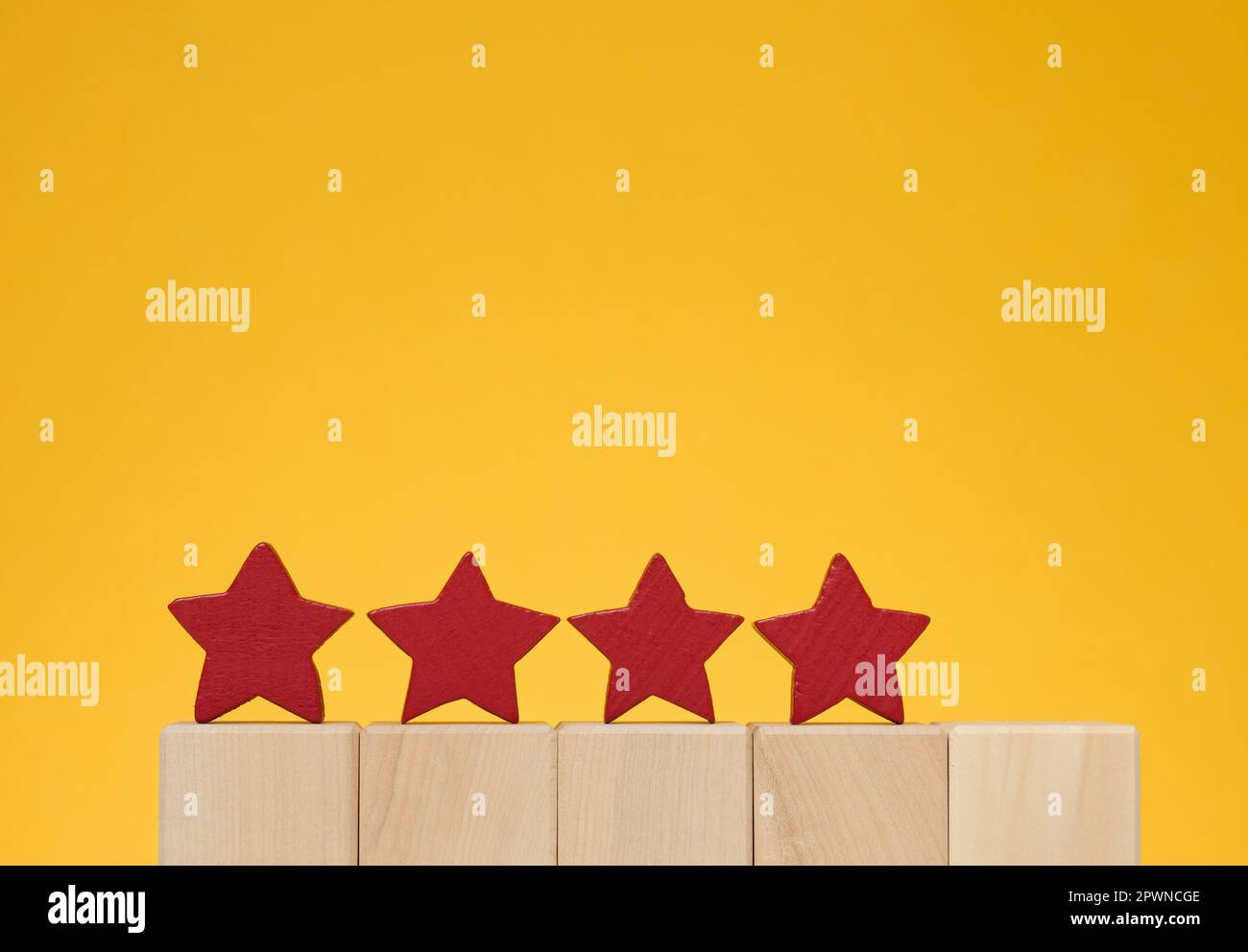 Four stars on wooden cubes, yellow background. Service evaluation ...