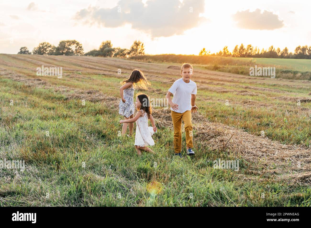 Little children run forward across field turning back. Carefree kids ...
