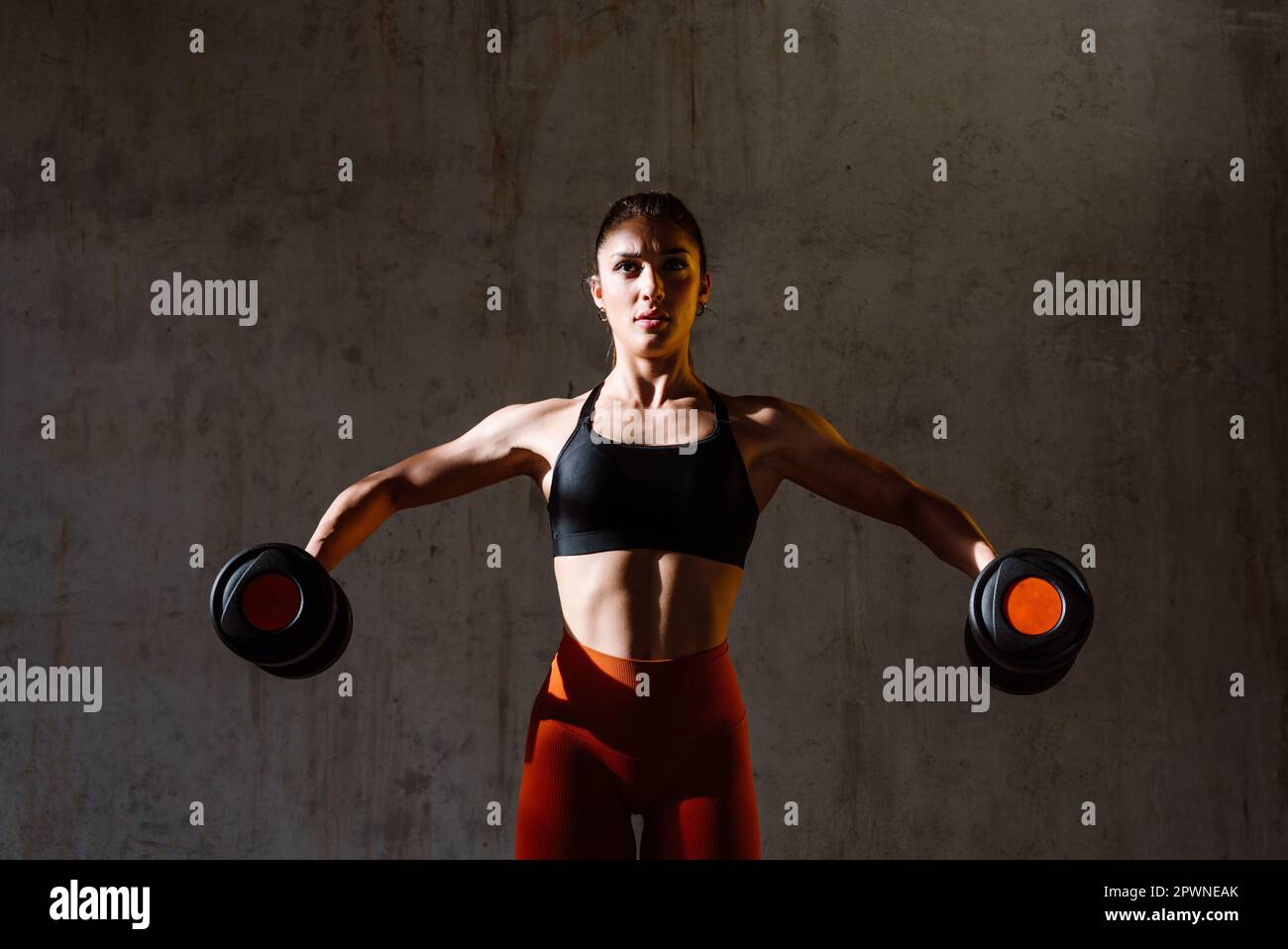 Young female athlete training in a gym using sport equipment. Fit woman ...
