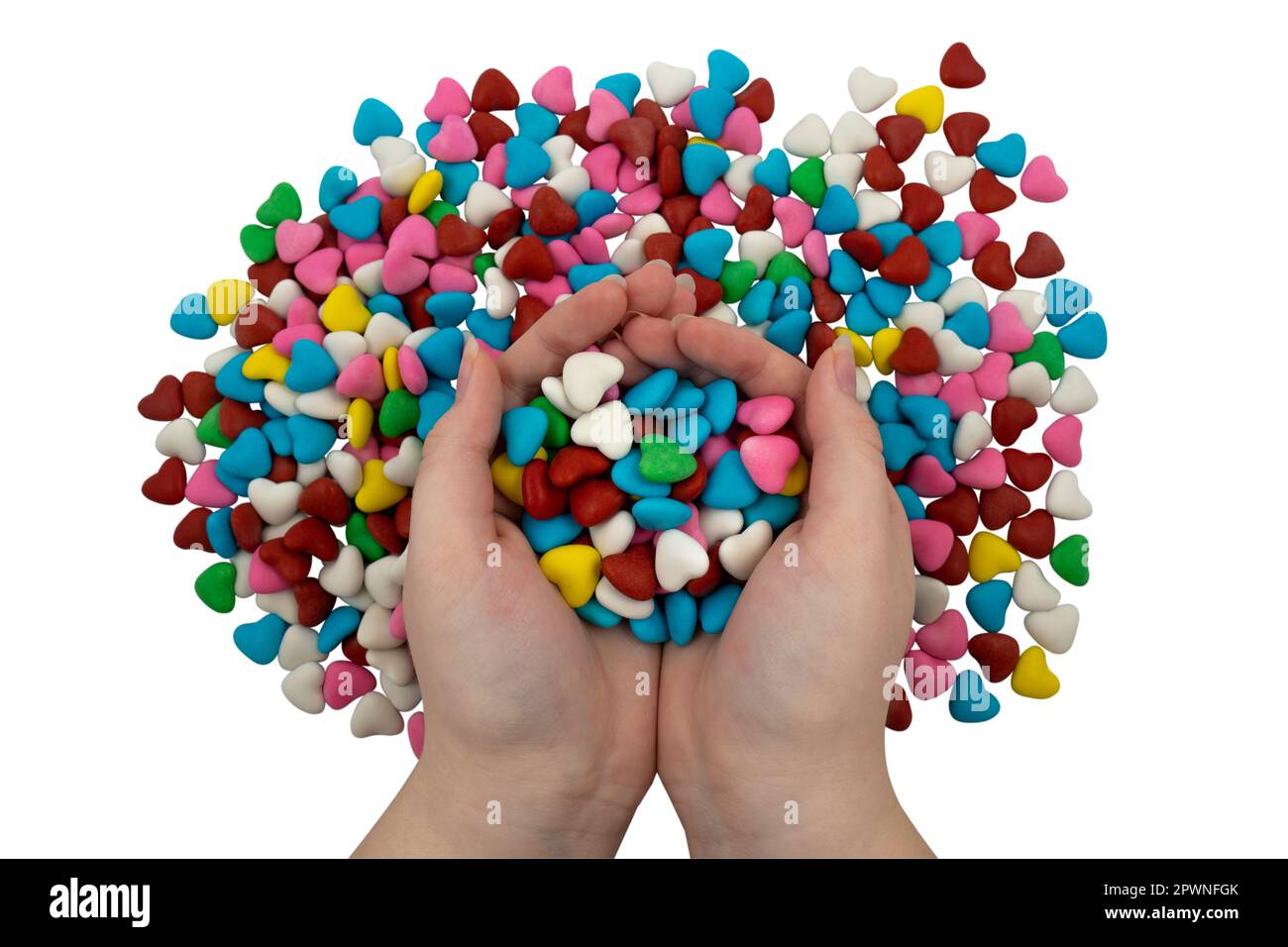 A handful of multi-colored heart-shaped candies in hands isolated on a ...