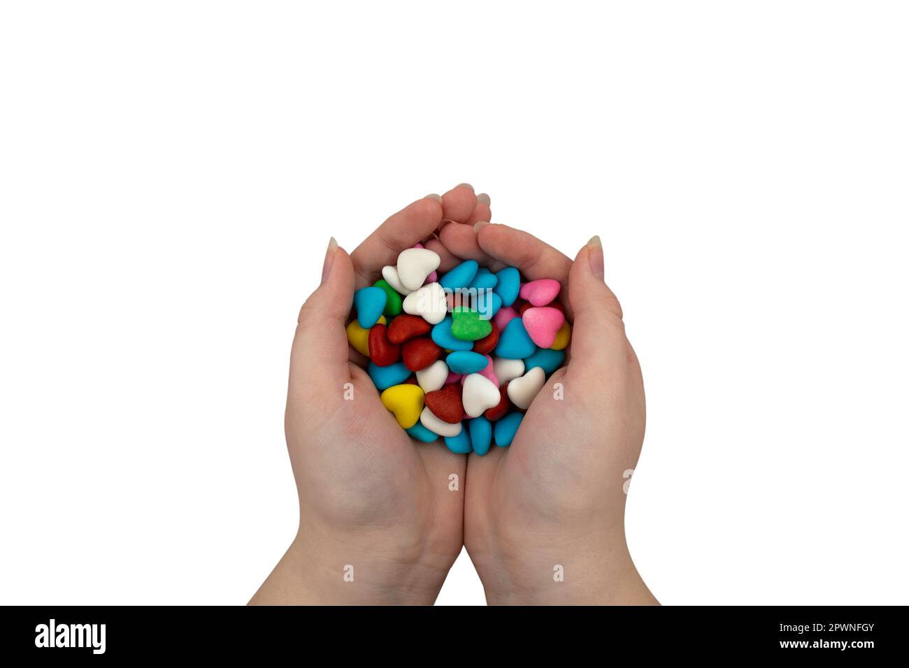 A handful of multi-colored heart-shaped candies in hands isolated on a ...