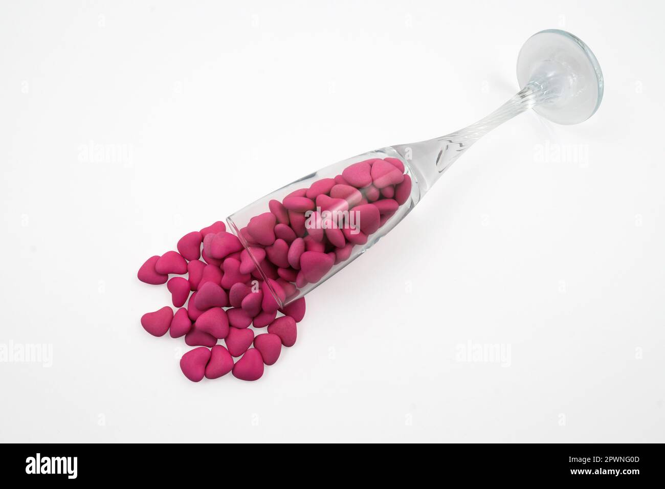 Overturned glass with heart shaped pink candies (close-up) isolated on ...