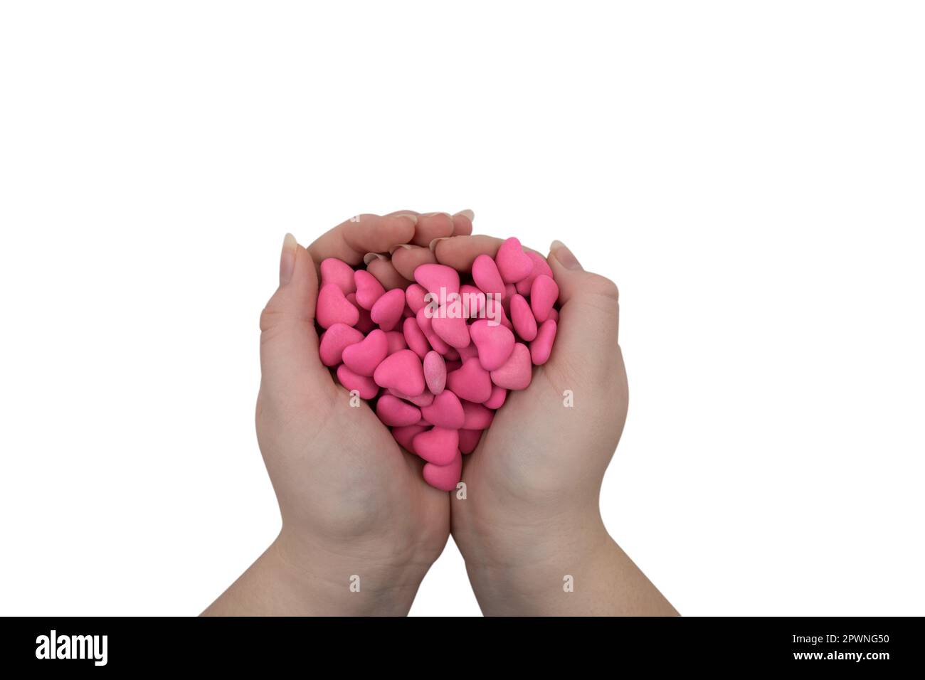 A handful of heart-shaped pink candies in hands isolated on a white ...