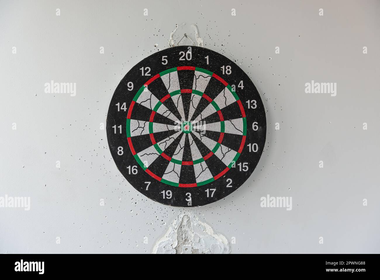 Old dartboard punctured by darts on gray wall. Background of an old ...