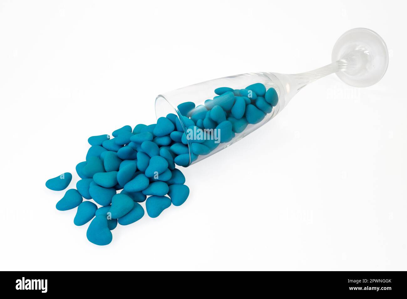 Overturned glass with heart shaped blue candies (close-up) isolated on ...