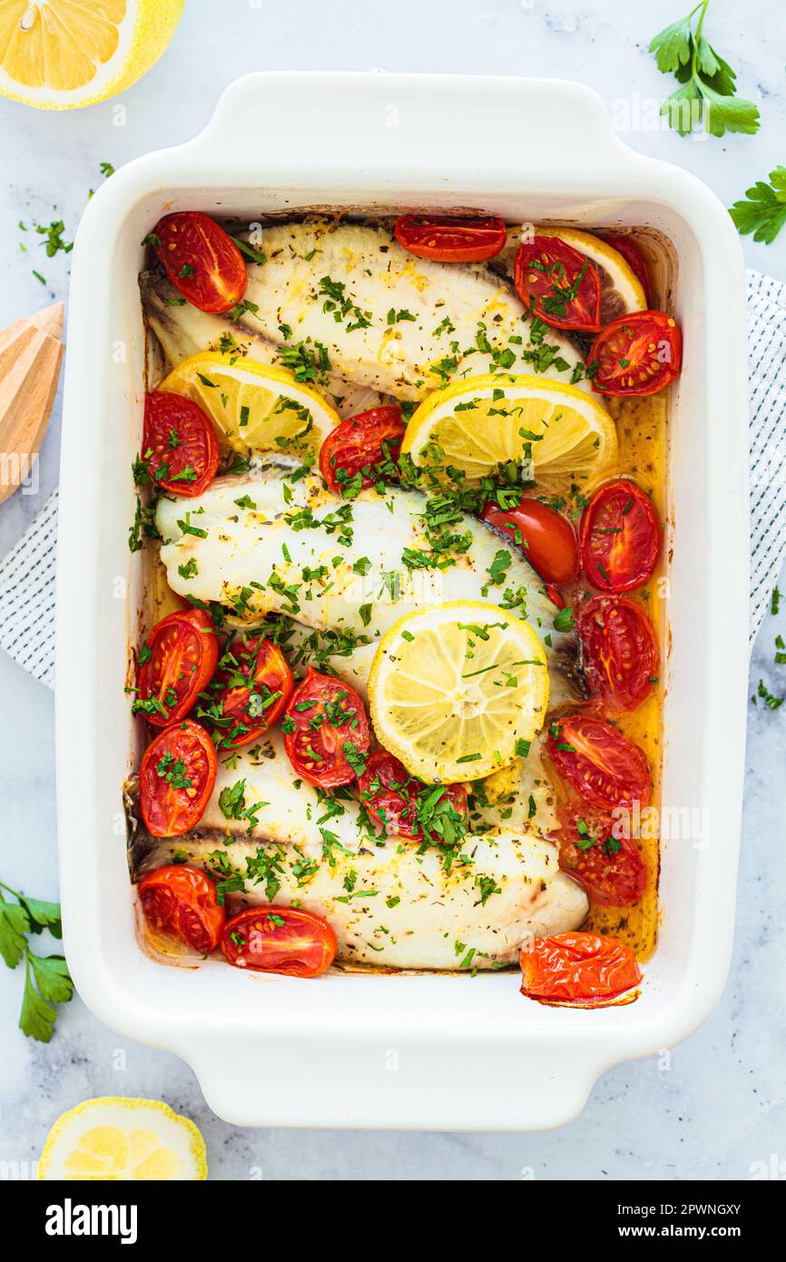 Baked cod fillet with cherry tomatoes and butter, top view. Healthy ...