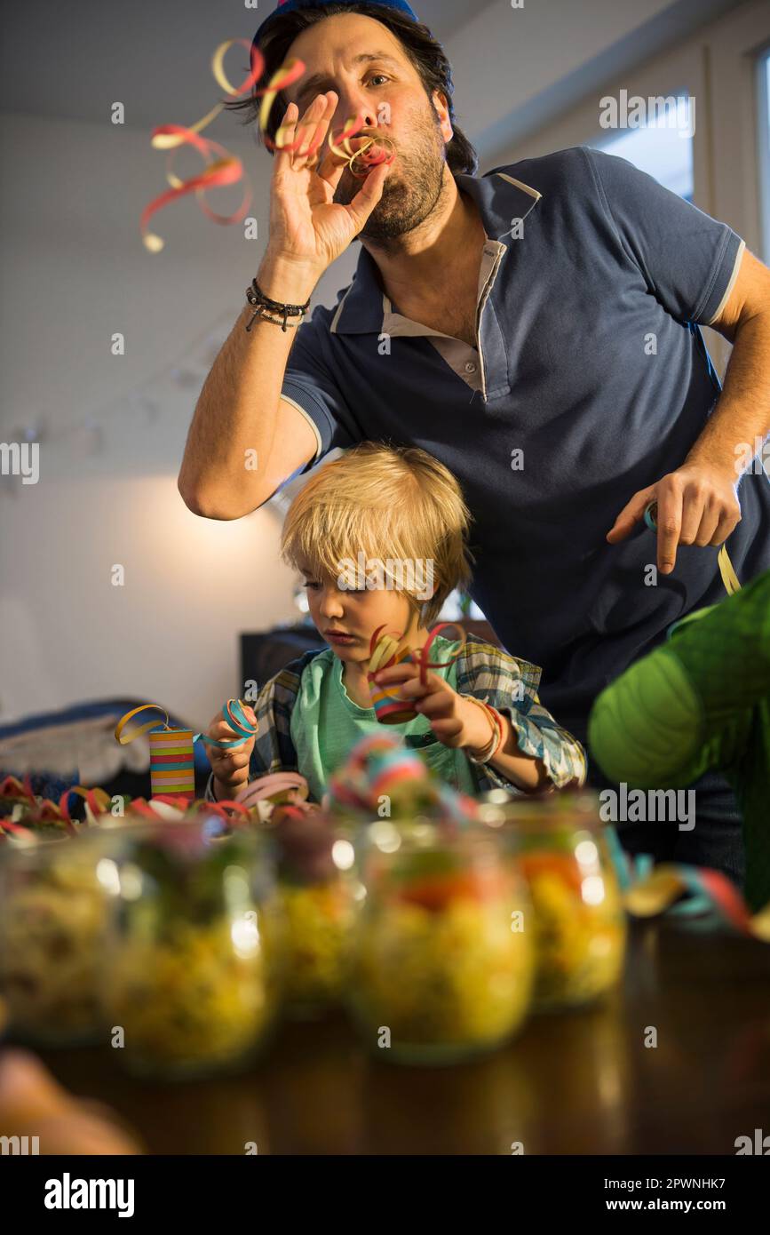 Father and son blowing paper streamers at a party Stock Photo - Alamy