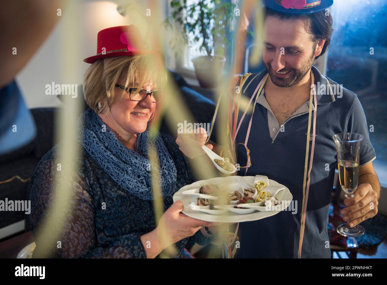 Woman offering food to guest at a party Stock Photo - Alamy