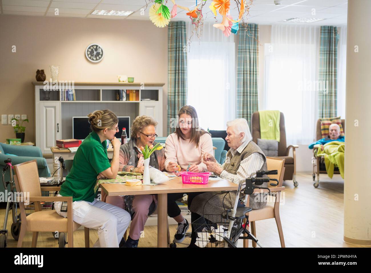 Senior women with girl and nurse doing craft activity at rest home ...