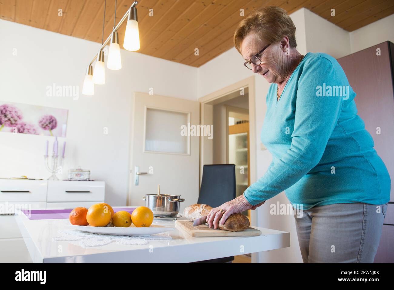 Old woman cutting bread on breakfast table Stock Photo - Alamy