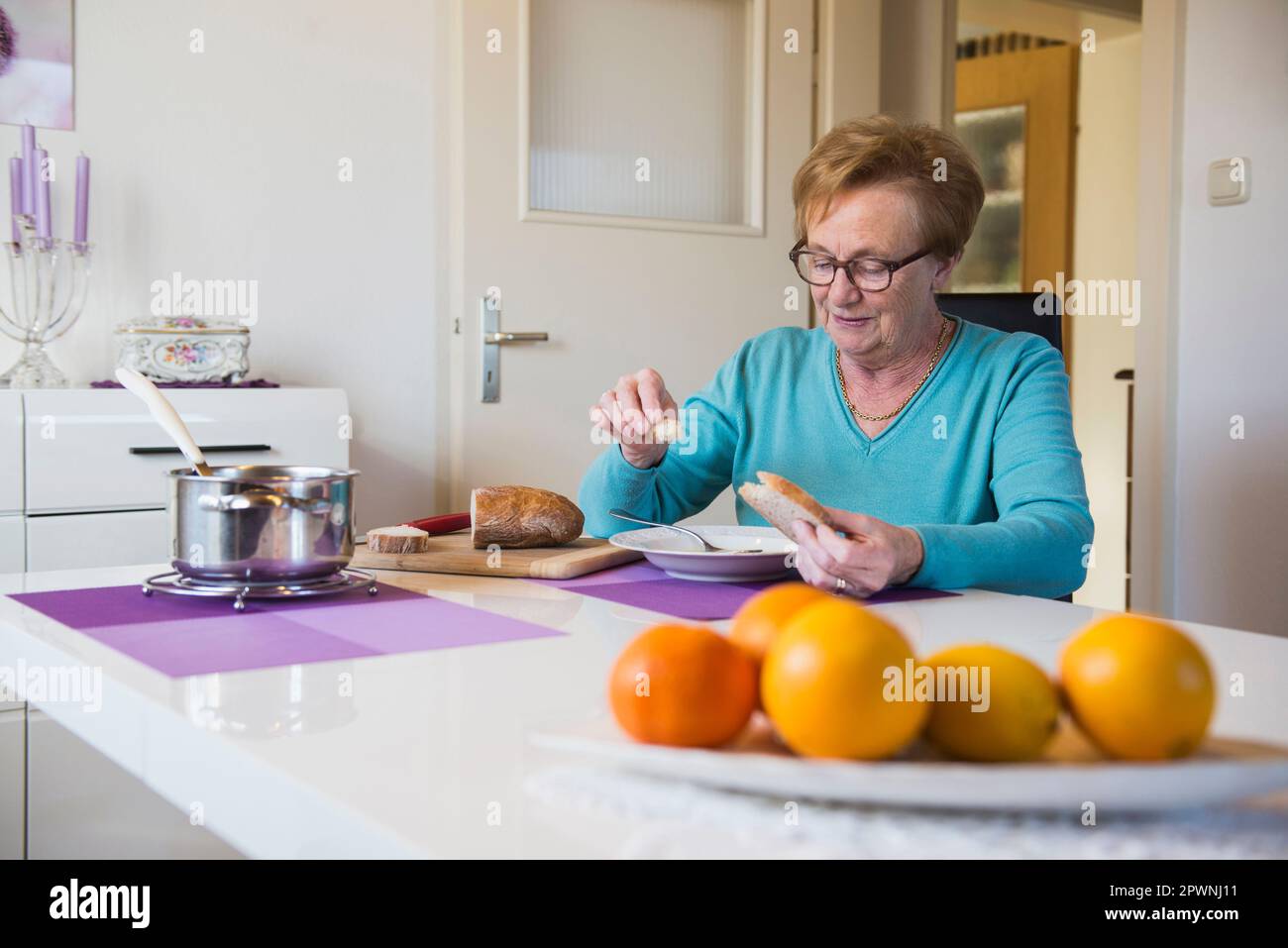 Old woman eating bread at lunch table Stock Photo - Alamy
