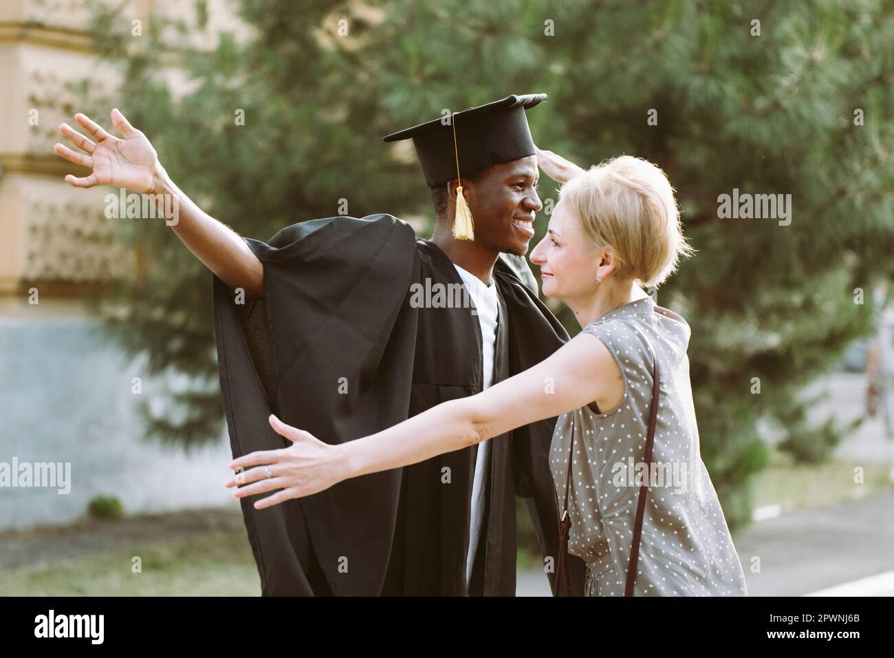Portrait of smiling afro american student in black graduation mantle ...
