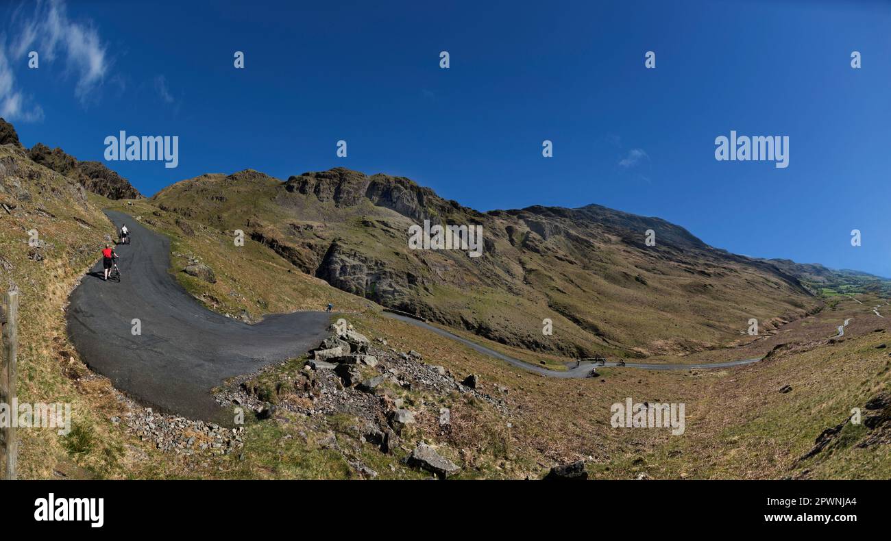 A cyclist pushes their bike up the steepest road in England, Hardknott ...