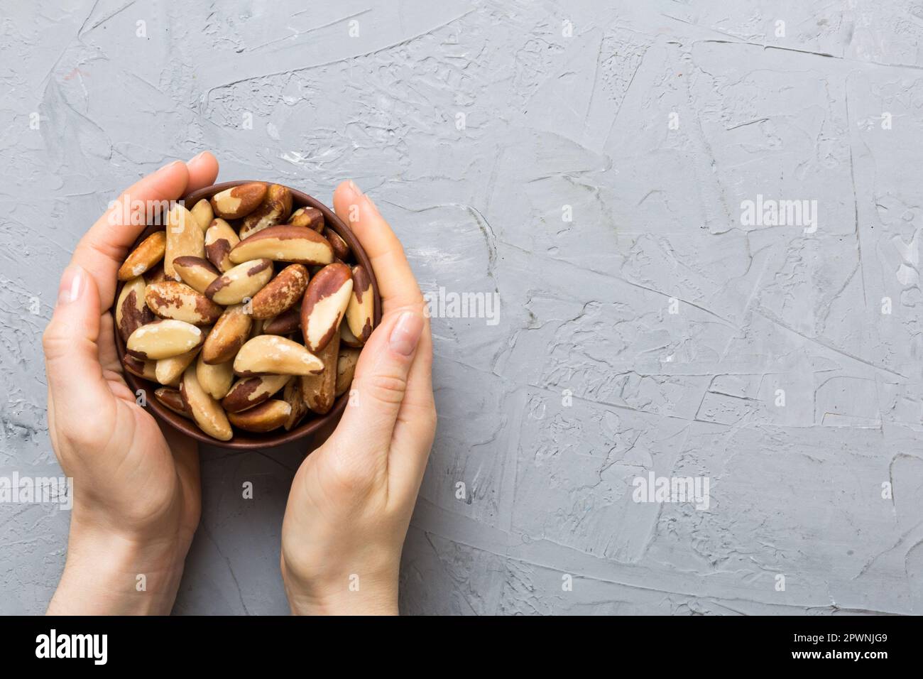 Woman hands holding a wooden bowl with brazil or bertholletia nuts ...
