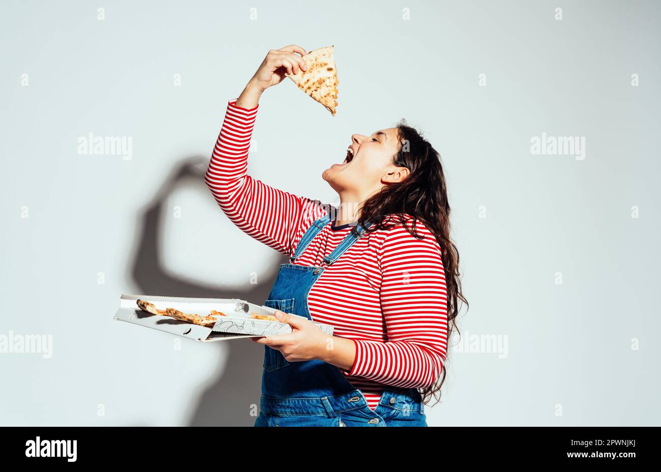 Plus size woman model posing in studio and having fun. Eating italian ...