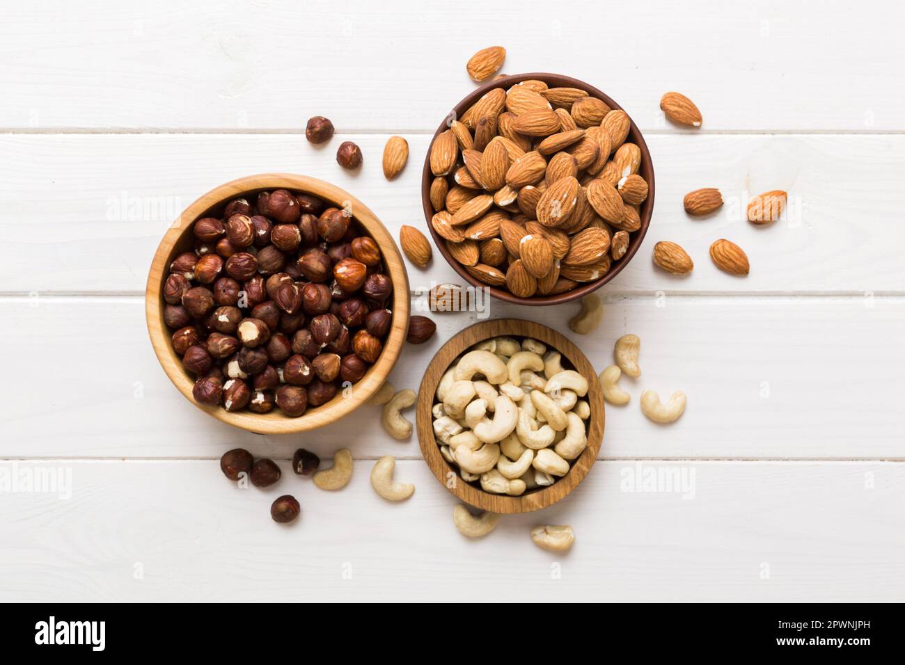 Assortment of nuts in wooden bowl on colored table. Cashew, hazelnuts ...