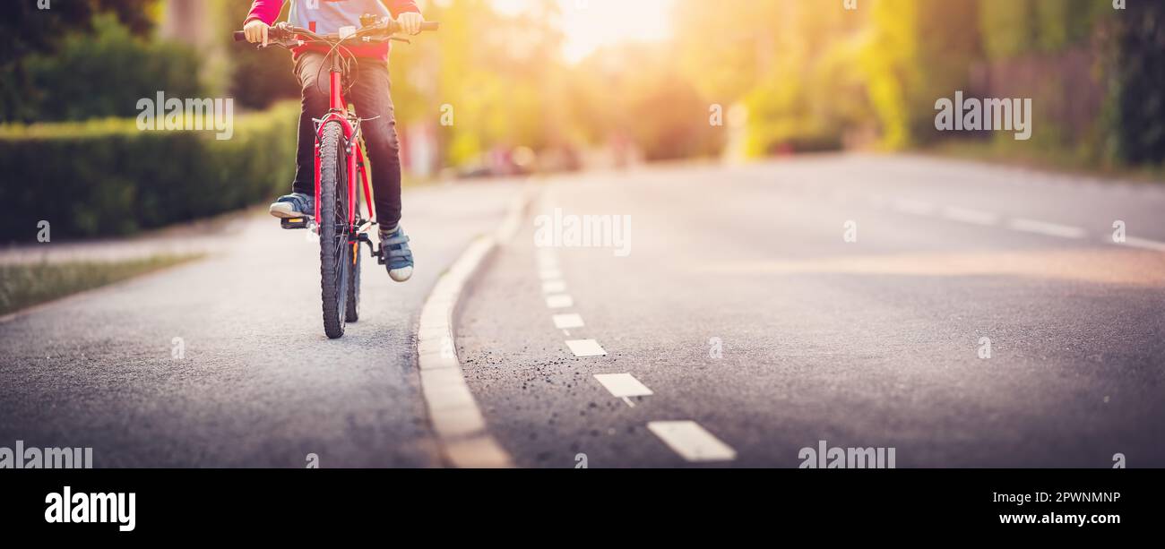 Boy riding a bike on the sidewalk along asphalt road. Concept of ...
