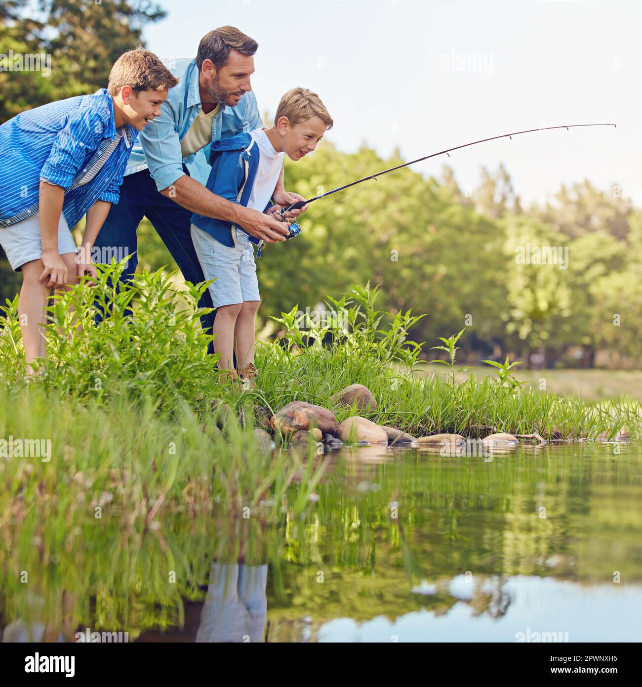 Showing them how to fish. a father and his two sons out fishing in the ...