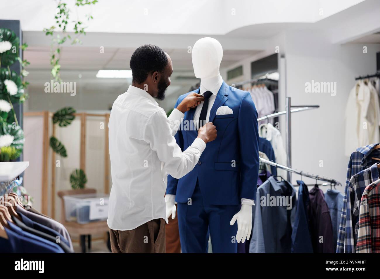 Clothing store stylist creating formal wear outfit on mannequin in ...