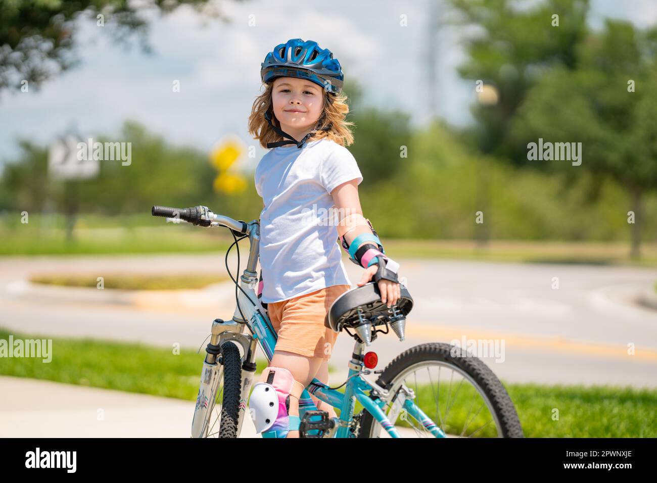 Child riding bicycle. Little kid boy in helmet on bicycle along bikeway ...