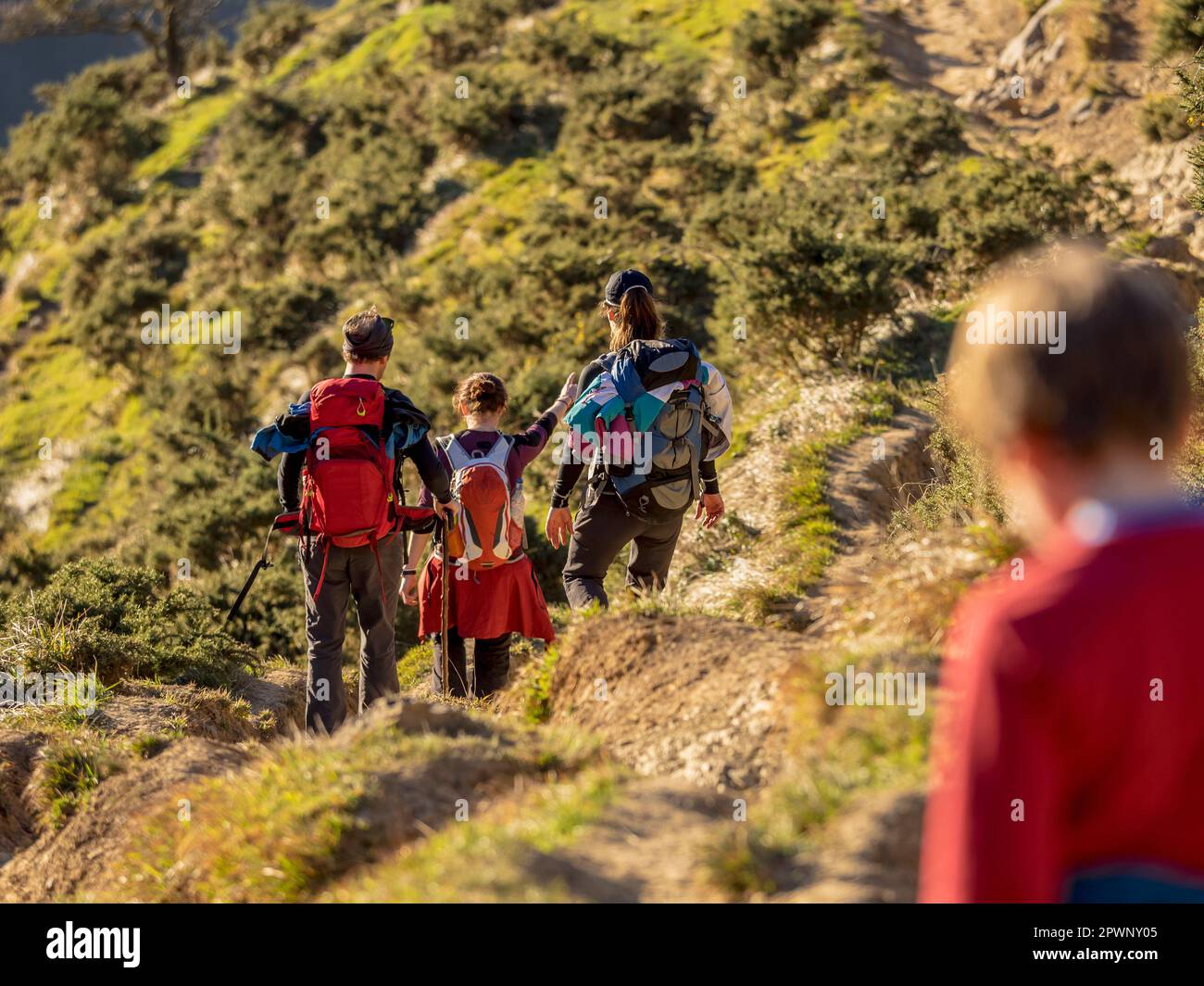 People hiking on a single trail towards the top of Txindoki Stock Photo ...