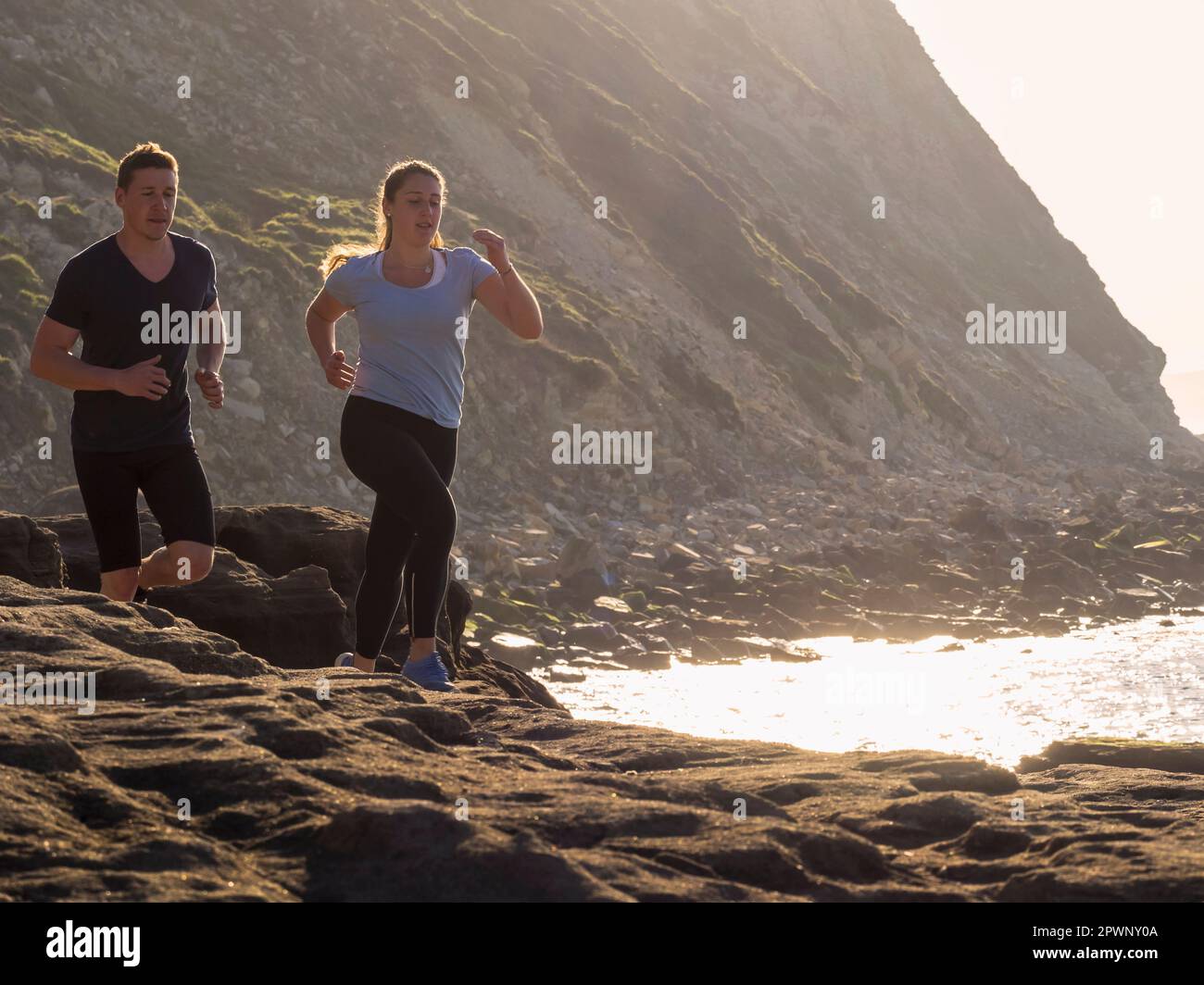 Man and woman running on single trail on coast at Azkorri beach Stock ...