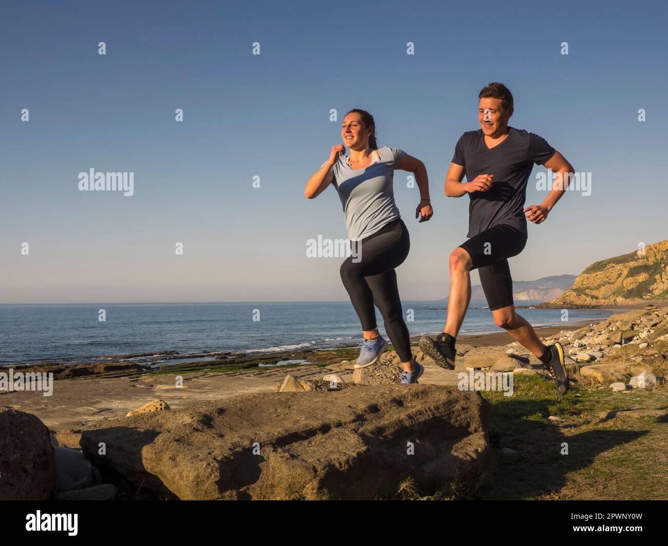 Man and woman running on single trail on coast of Azkorri beach Stock ...