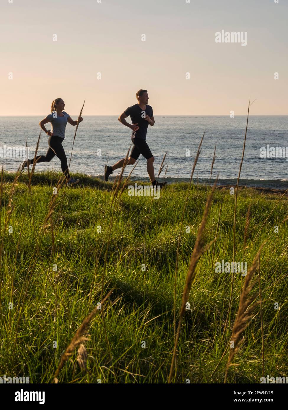 Man and woman running on single trail on coast of Azkorri beach Stock ...