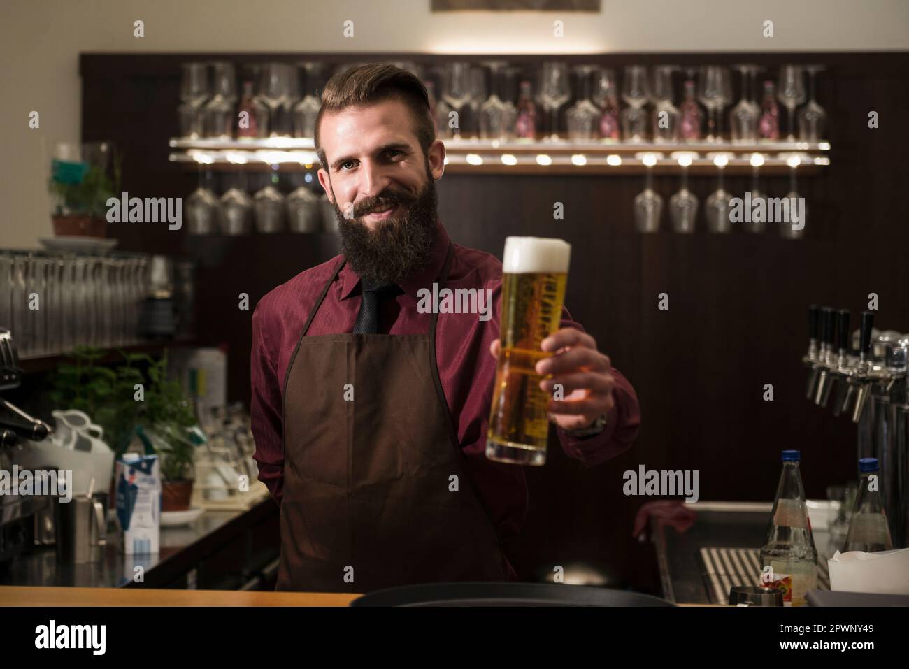 Portrait of young man offering glass of beer Stock Photo - Alamy