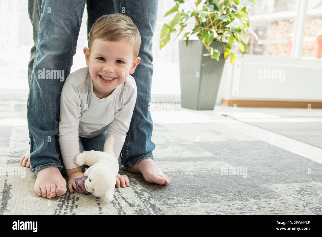 Little boy crawling between parents legs Stock Photo - Alamy