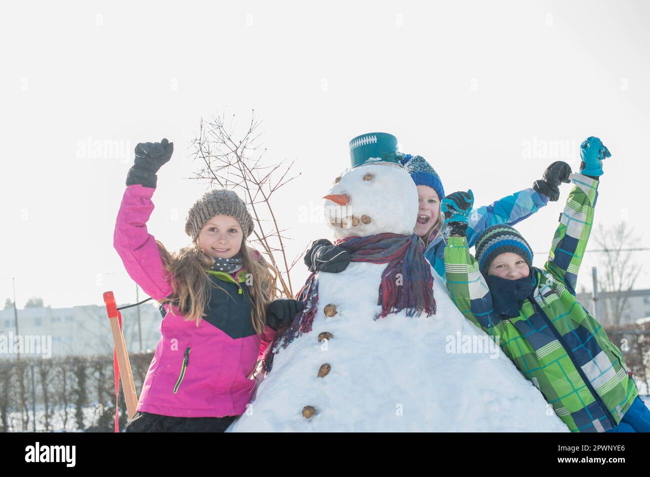 Portrait of children leaning on snowman with raised arms Stock Photo ...