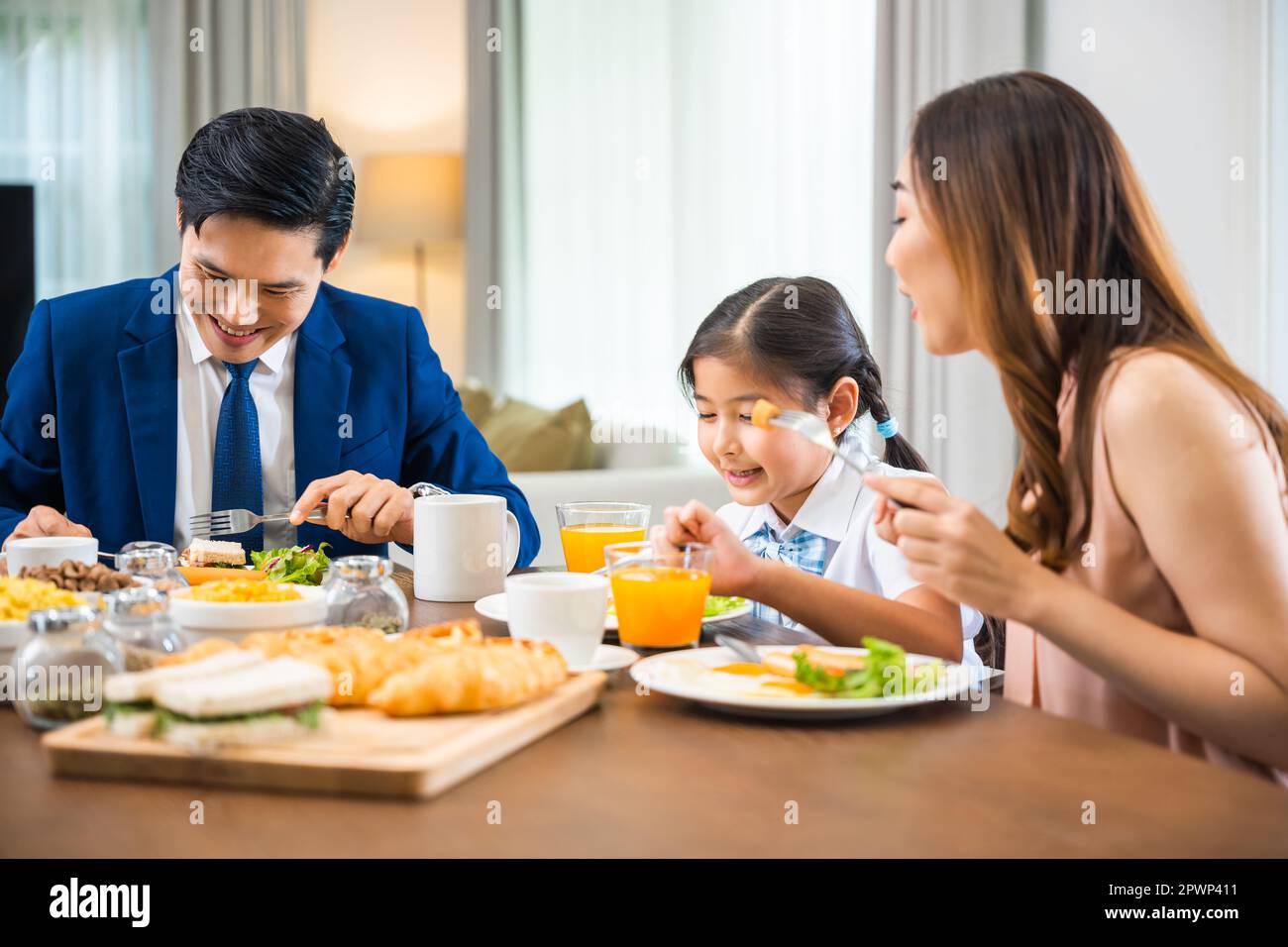 Asian family father, mother with children daughter eating breakfast food on dining table kitchen ...