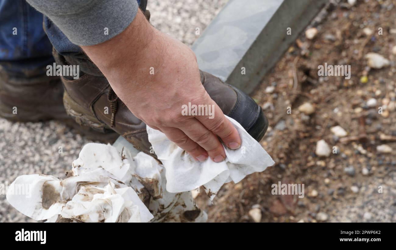 Tourist cleaning his dirty brown laced boots. Men's boots in mud ...