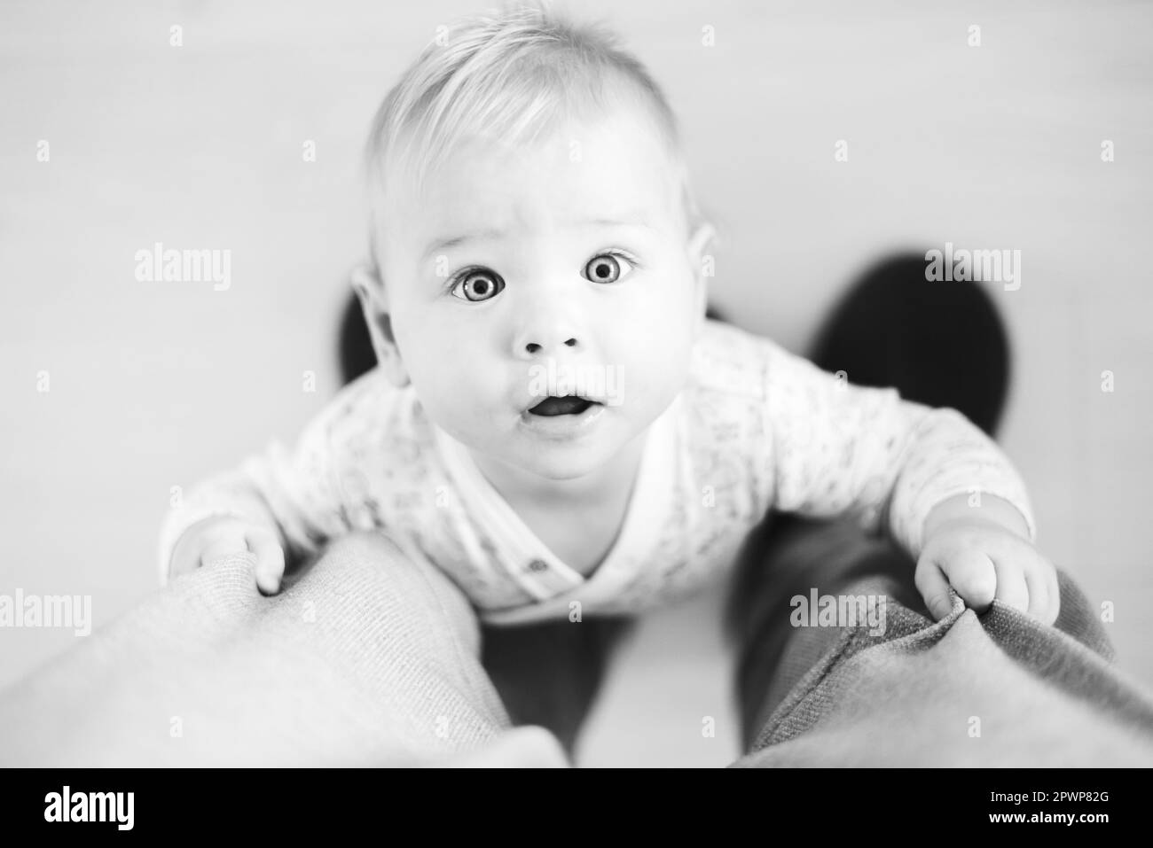 Top down view of cheerful baby boy infant taking first steps holding to ...