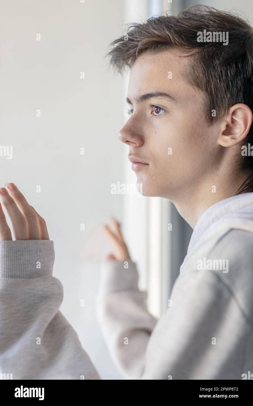 Teenage boy looking thoughtfully out the window Stock Photo - Alamy