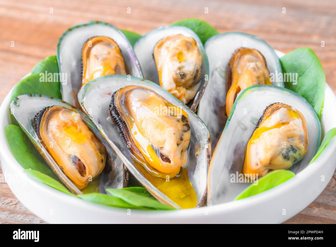 Bowl of baked half shell mussels on wooden background Stock Photo - Alamy