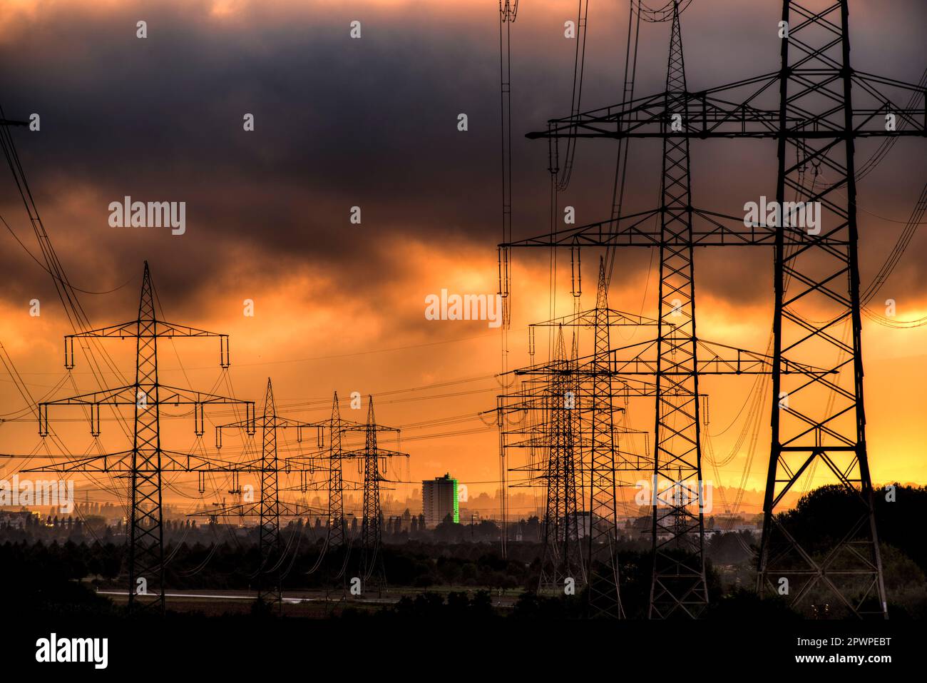 Silhouettes of power poles of a power line against atmospheric orange ...