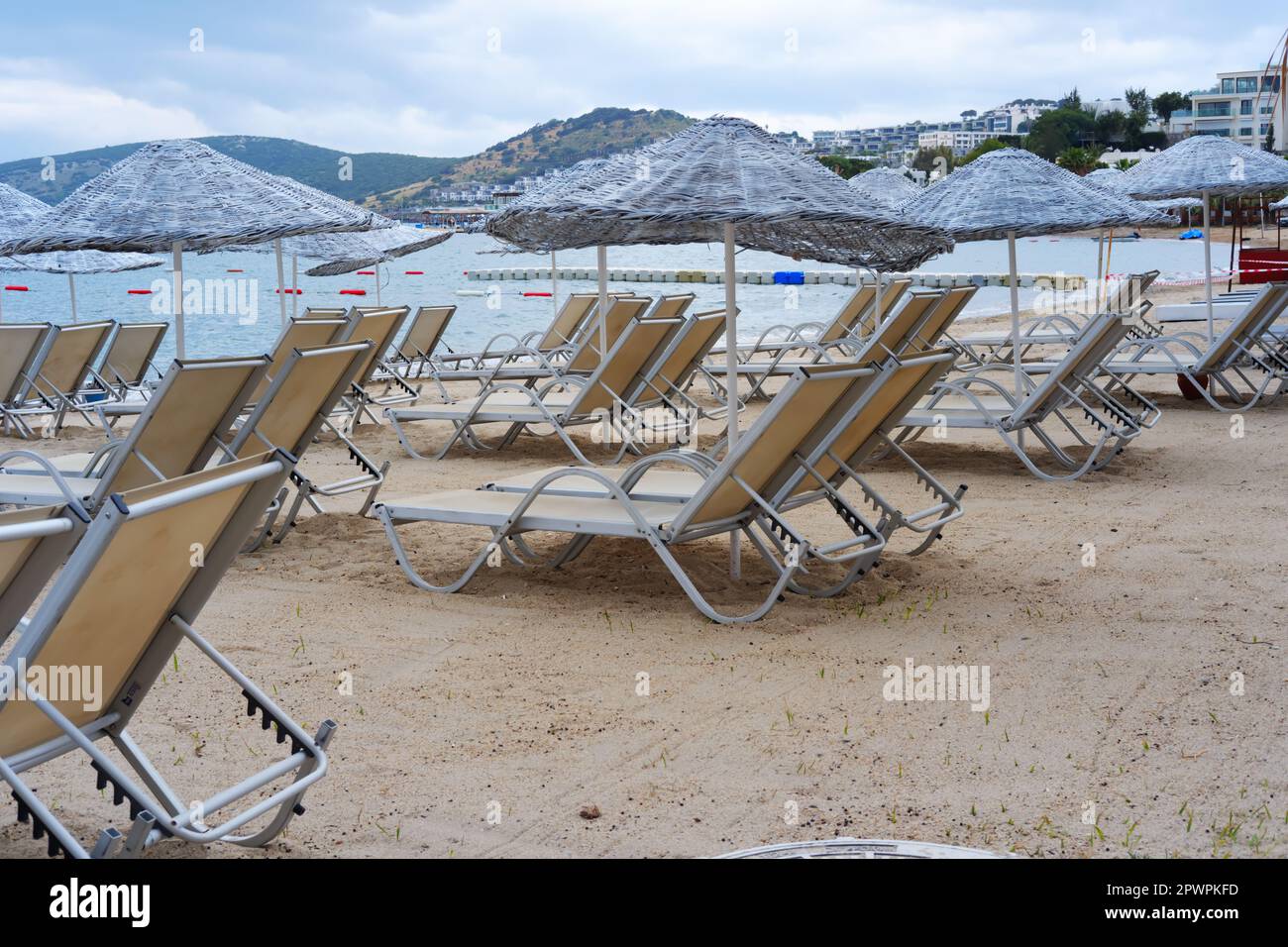 Empty seabeds at sandy beach with bambu umbrellas. Hills and trees at ...