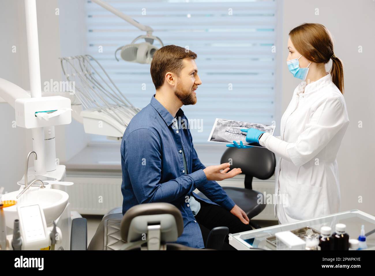 Young attractive man visiting dentist, sitting in dental chair at ...