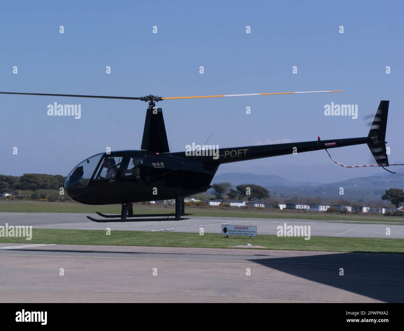 Two tourists and pilot in R44 Raven 11 black helicopter taking off from ...