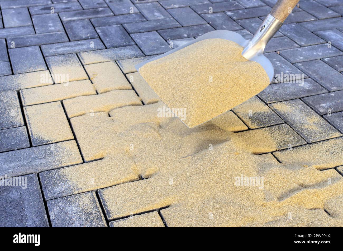 Sweeping in joint sand on a construction site Stock Photo - Alamy